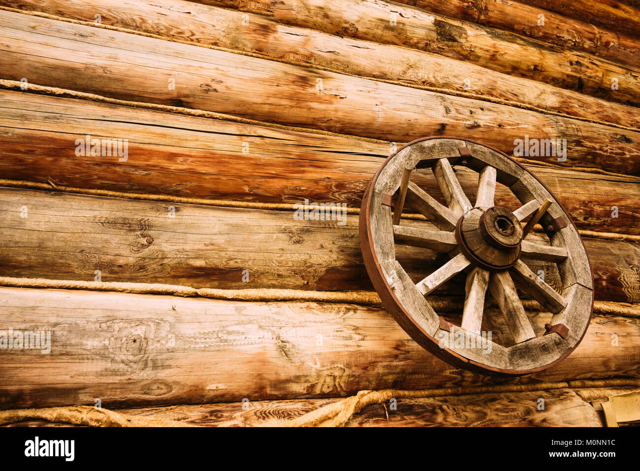 Old wooden wheel on the log wall Stock Photo - Alamy