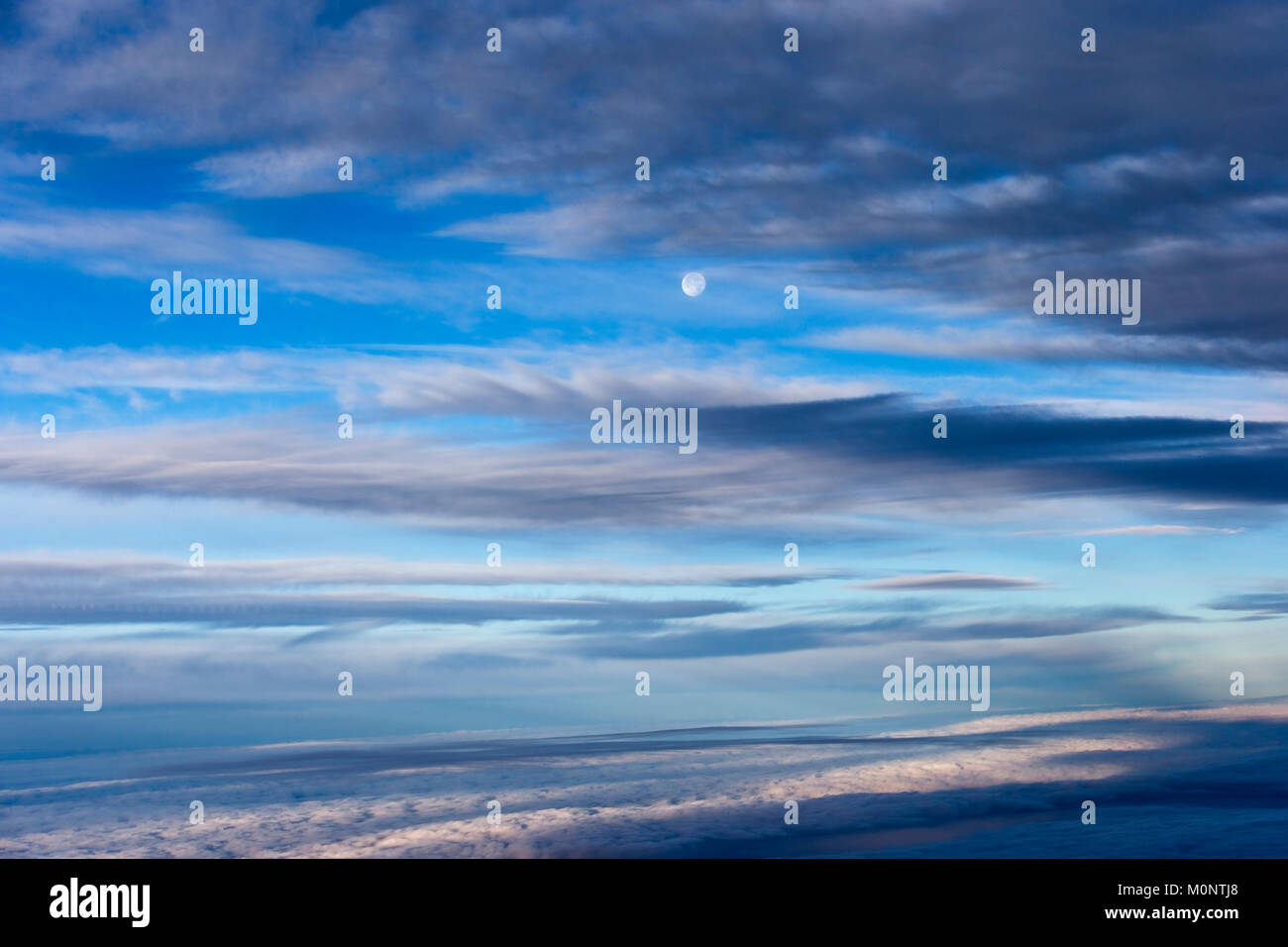 Cloudscape, in-flight shot of the early morning sky with the Moon Stock ...
