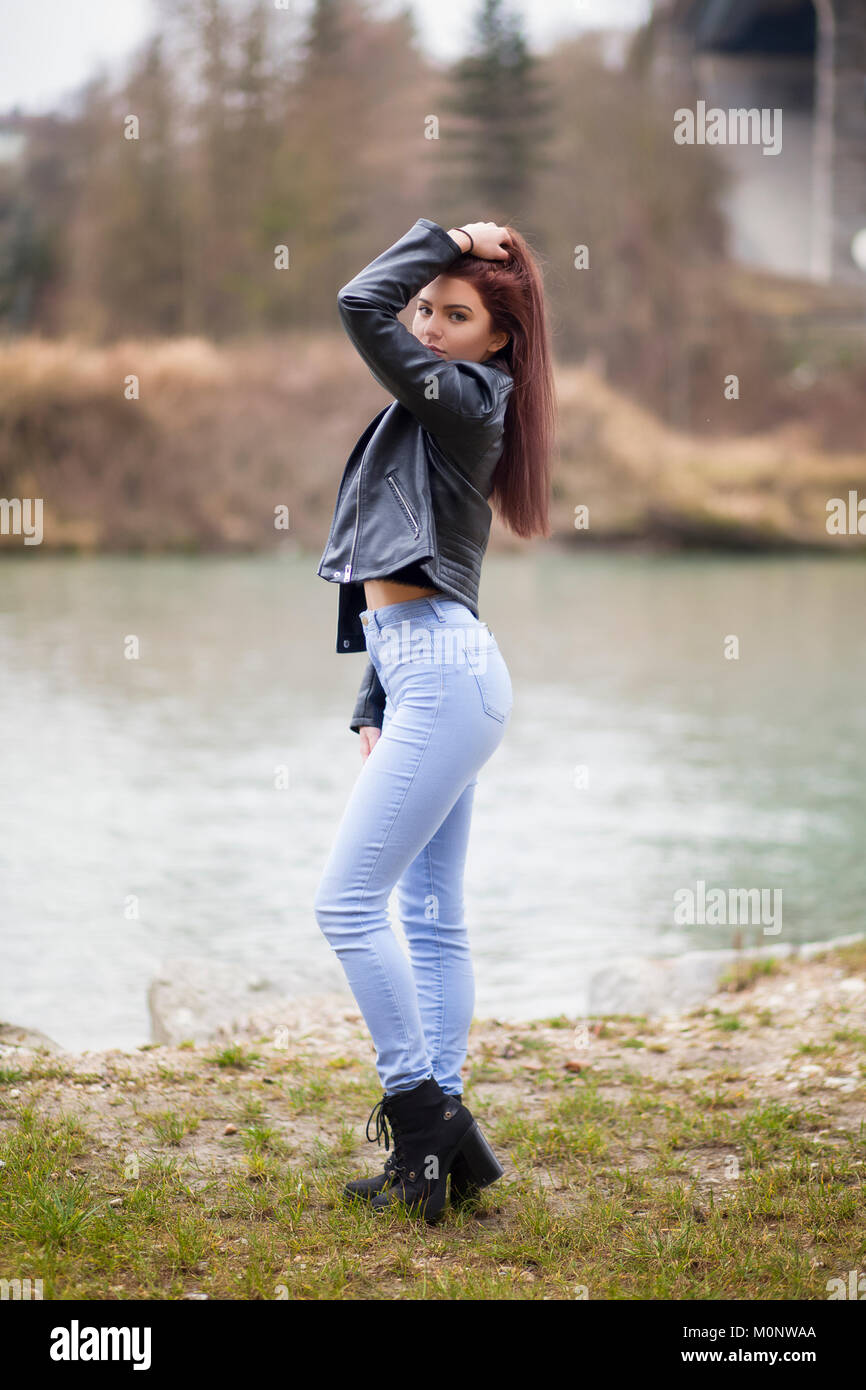Full length side view of a beautiful young woman wearing leather motor ...