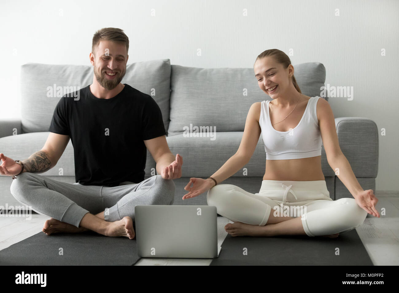 Smiling couple learning yoga exercises watching video on laptop Stock ...