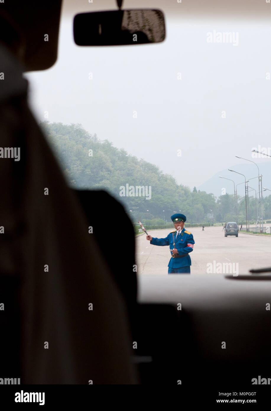 North Korean policeman controlling entrance to the city on the highway ...