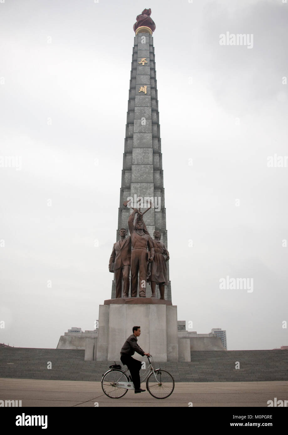 North Korean man cycling in front of the Juche tower built to ...