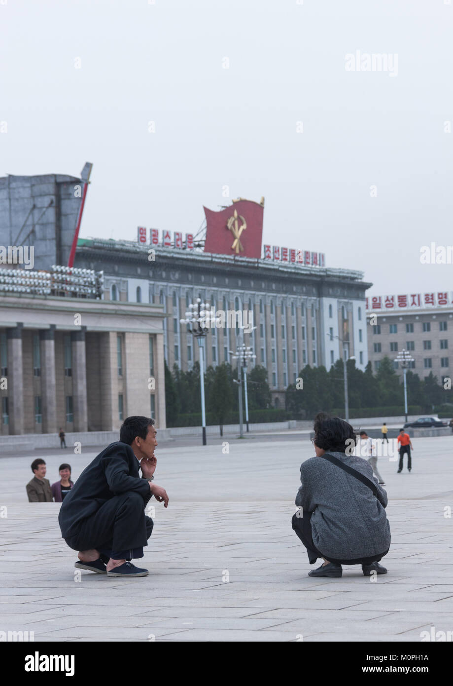 North Korean men squatting on Kim il Sung square, Pyongan Province ...