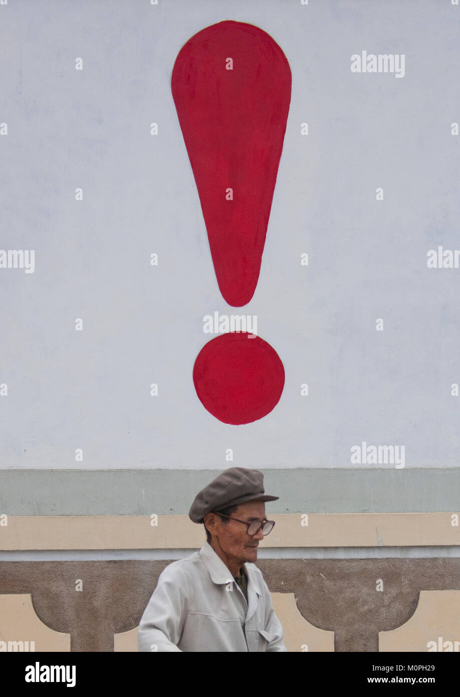 Senior North Korean man walking in the street under an exclamation mark ...