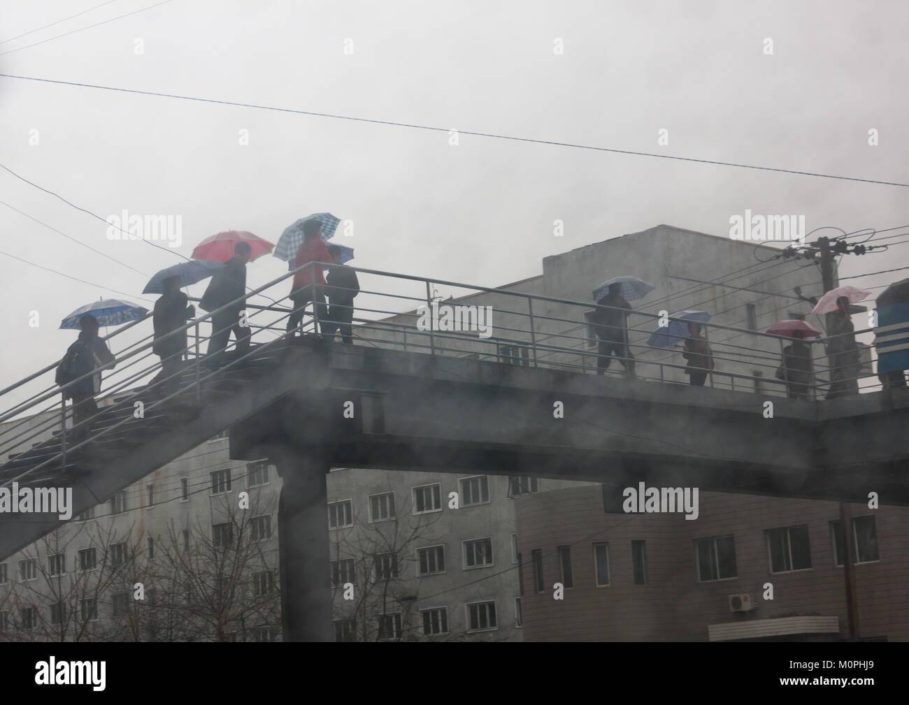 North Korean pedestrians crossing a bridge under the rain, Pyongan ...