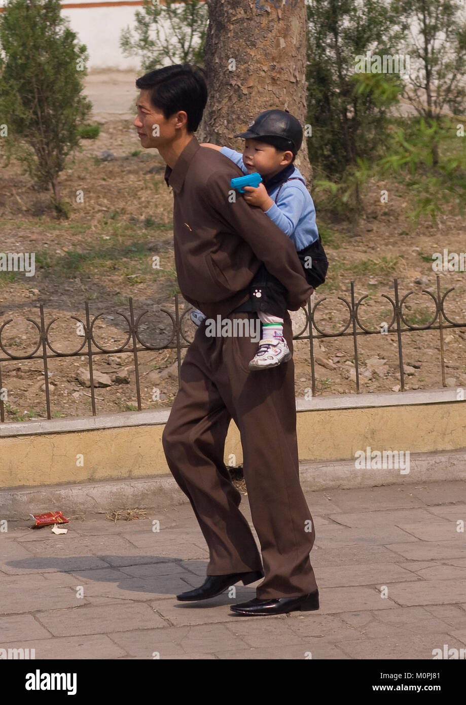 North Korean father walking in the street with his son on his back ...