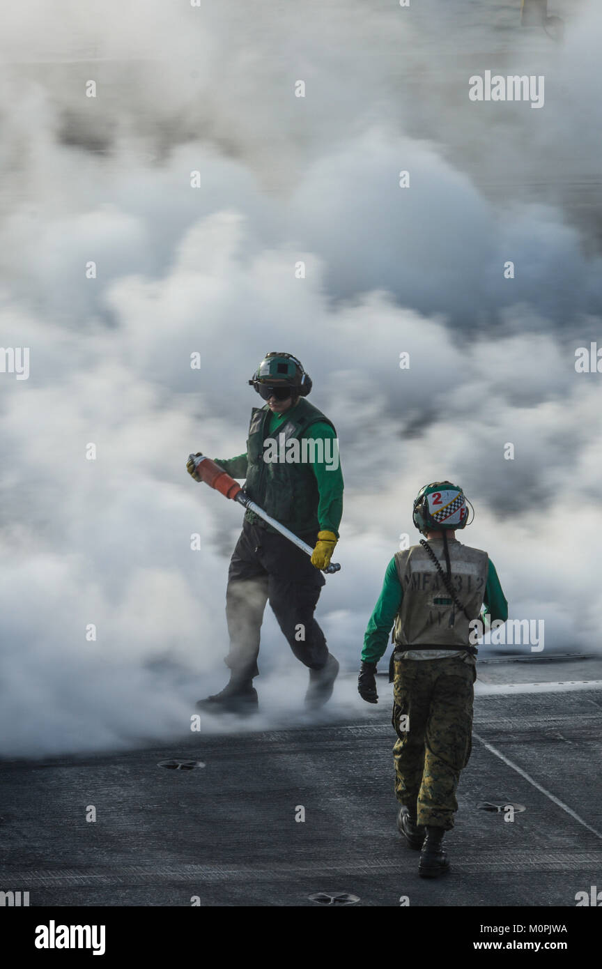 A Sailor and Marine ready an aircraft catapult during flight operations ...