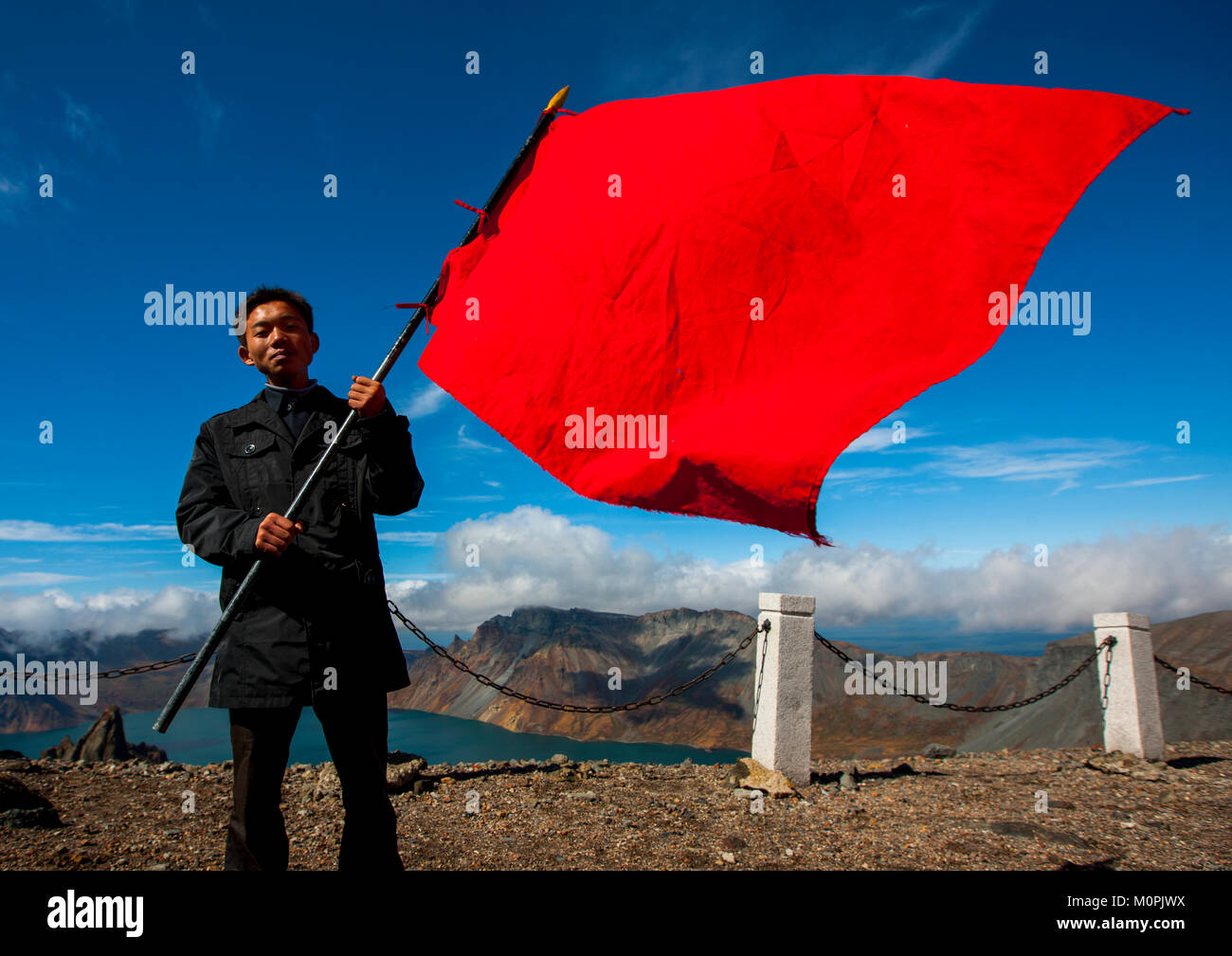 North Korean student holding a big red flag at the top of mount Paektu ...
