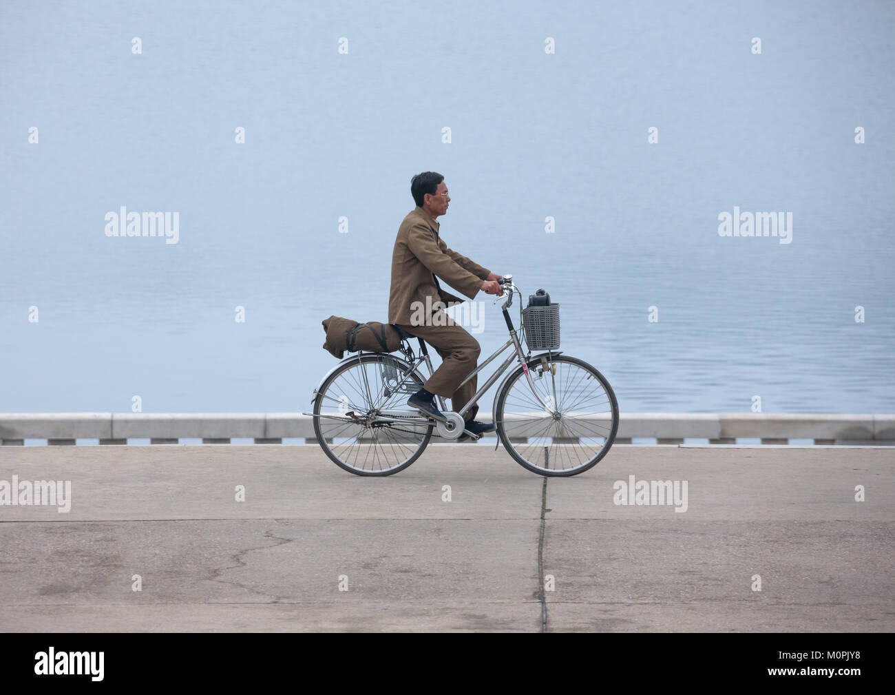 North Korean man riding a bicycle along Taedong river, Pyongan Province ...