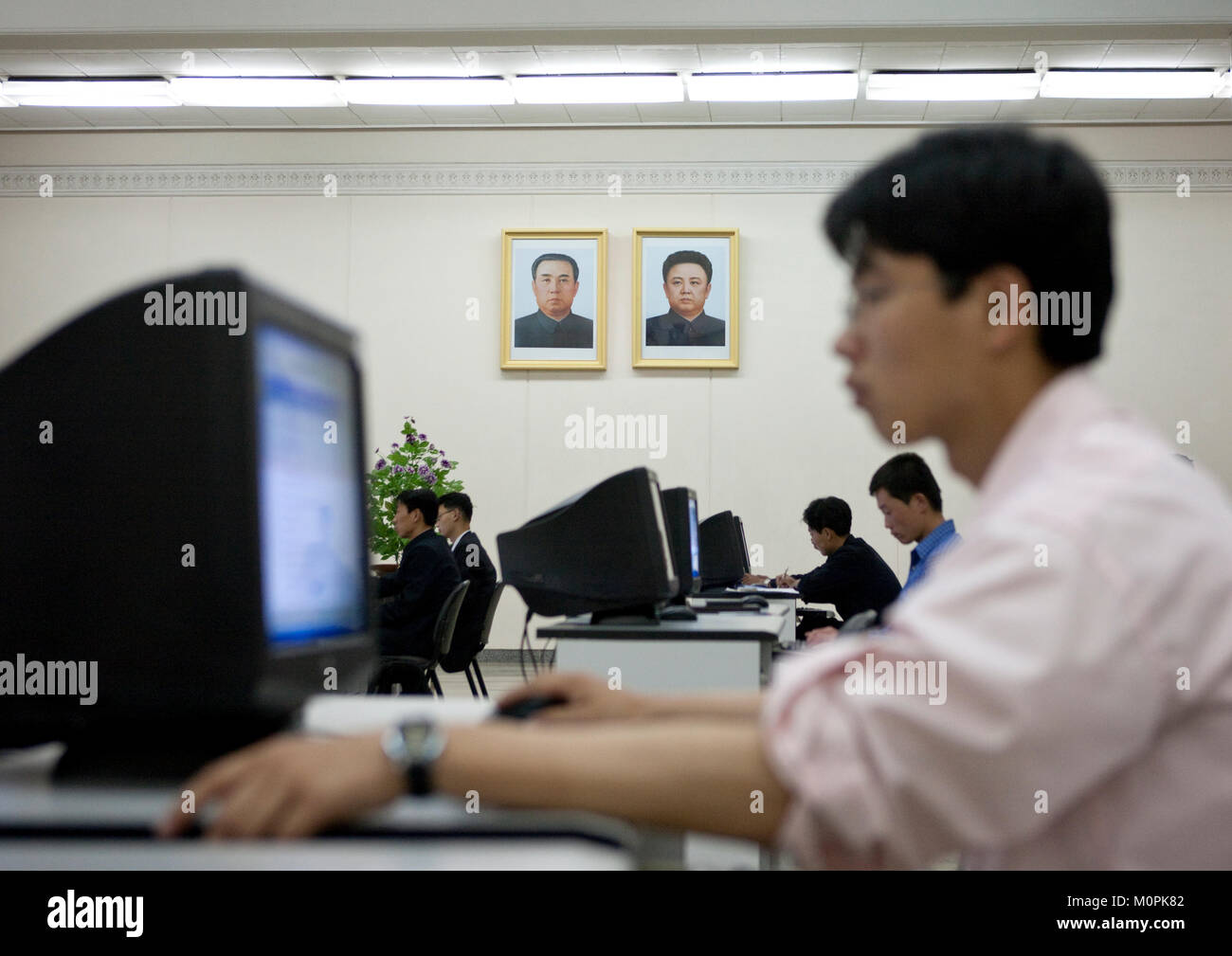 North Korean man using a computer under the Dear Leaders pictures in ...