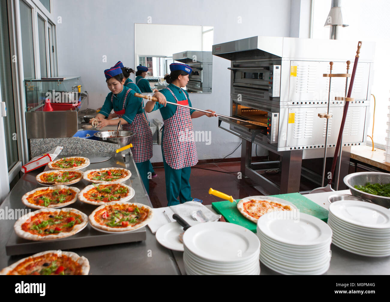 North Korean pizzeria cook putting a pizza in the oven in an italian ...