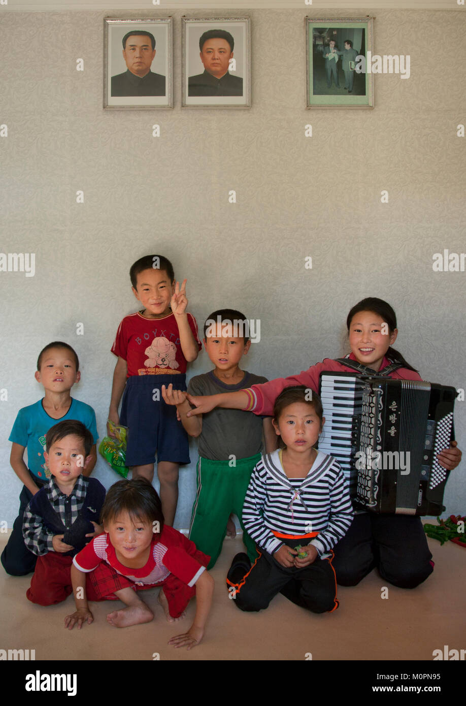 Group of children posing under Kim Jong il and Kim il Sung portraits in ...