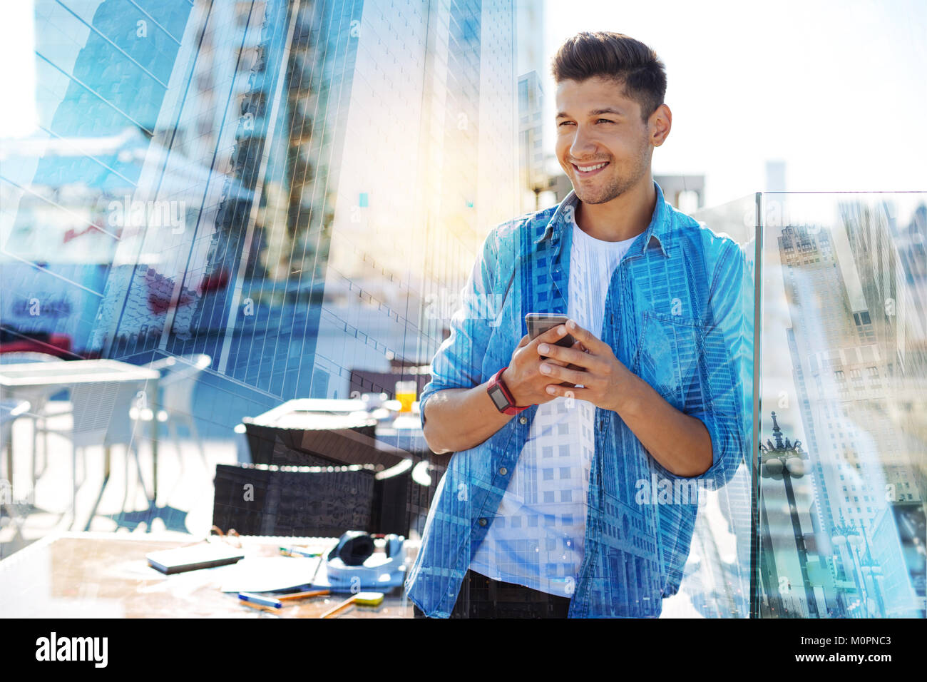 Cheerful man holding his phone and smiling Stock Photo - Alamy