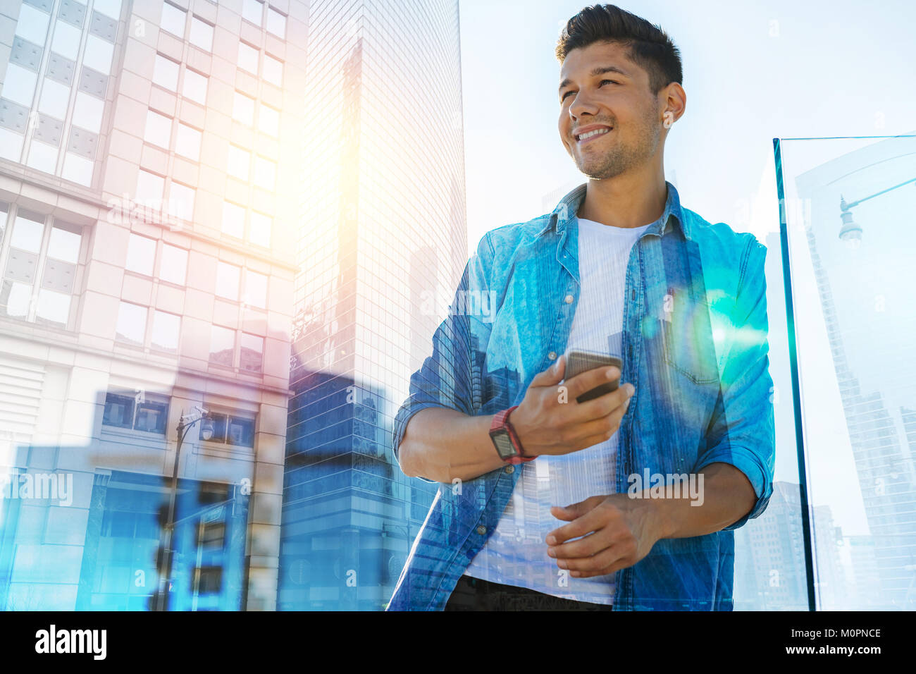 Content man holding his phone and smiling Stock Photo - Alamy