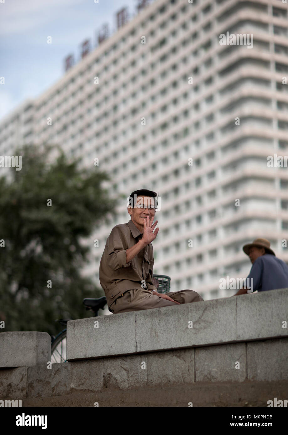 North Korean man sit on a wall waving hand, Pyongan Province, Pyongyang ...