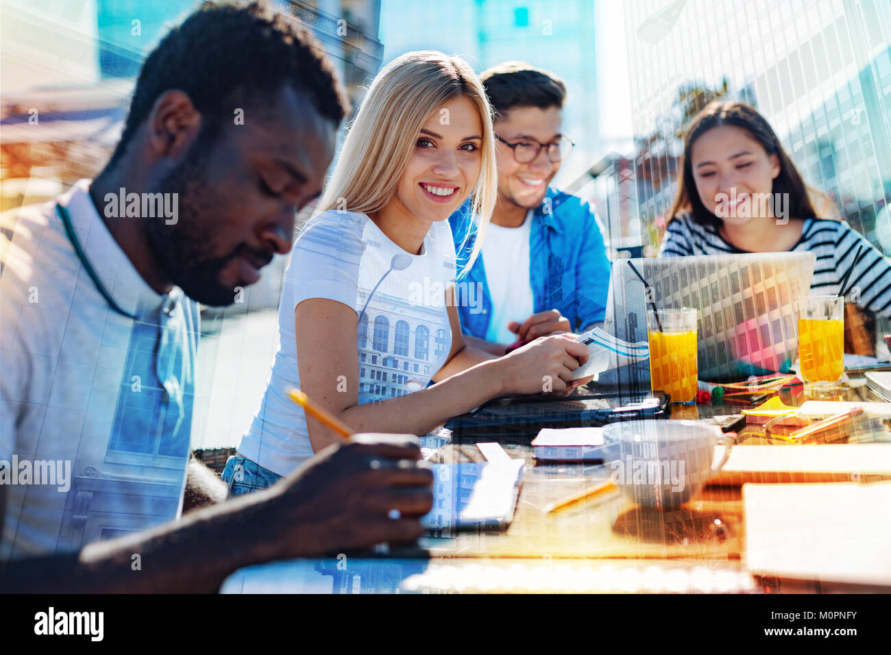 Smiling girl working on a project with her co-workers Stock Photo - Alamy