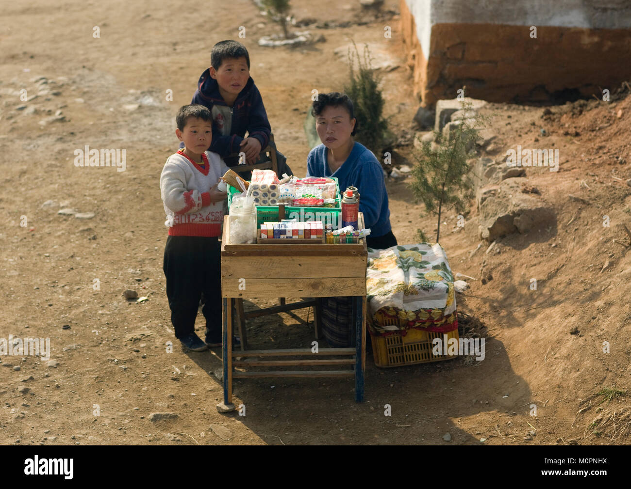North Korean woman with her children selling food and cigarettes along ...