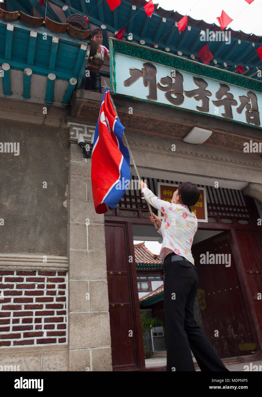 North Korean woman raising flag on a restaurant, North Hwanghae ...