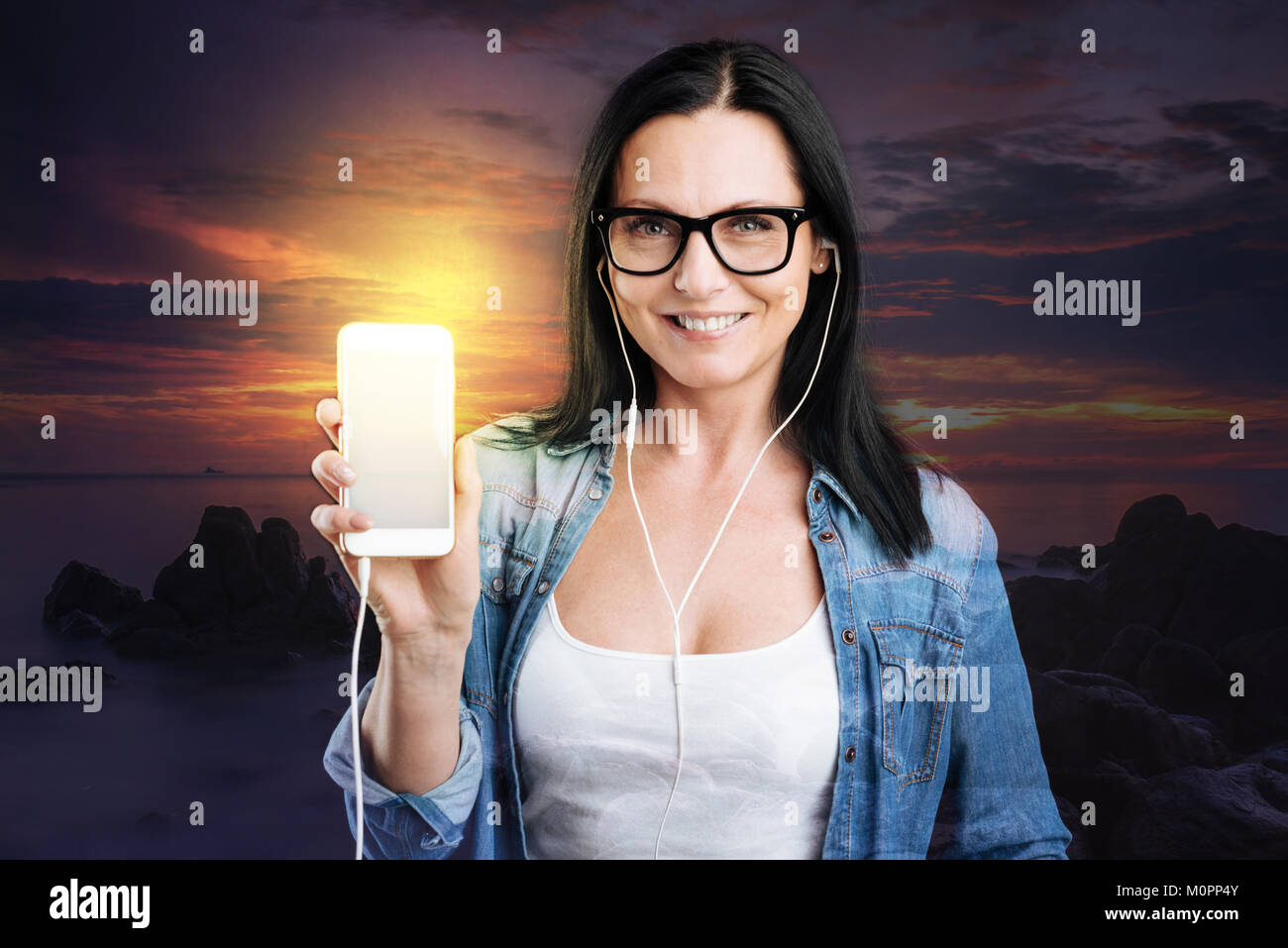 Smiling lady showing her smartphone into camera Stock Photo - Alamy
