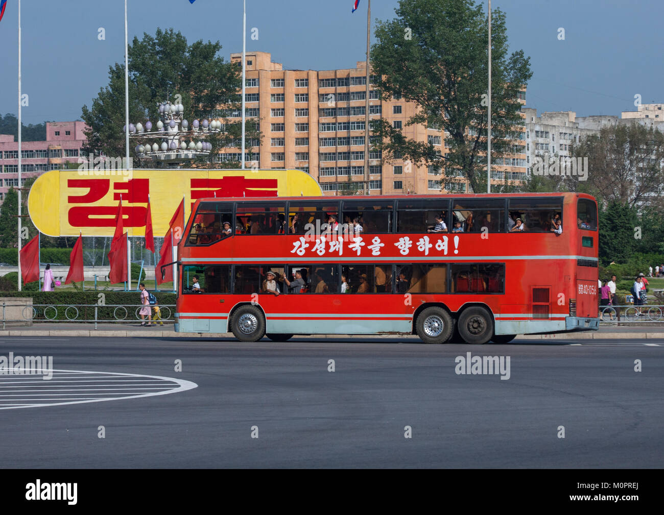 Double deck bus passing in front of a propaganda billboard in the city ...
