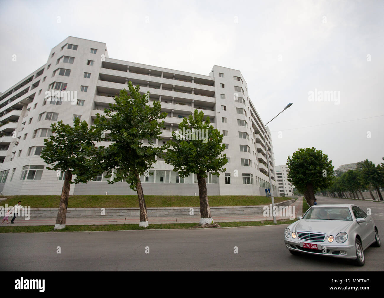 Mercedes on the road passing in front of luxury apartment block ...