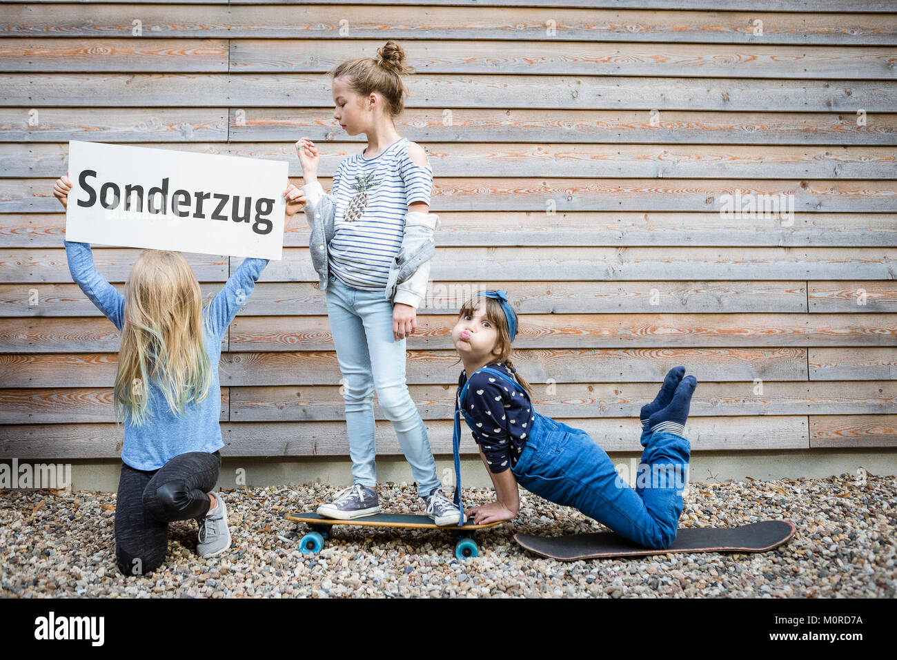 Three girls playing together in front of a wooden facade Stock Photo ...