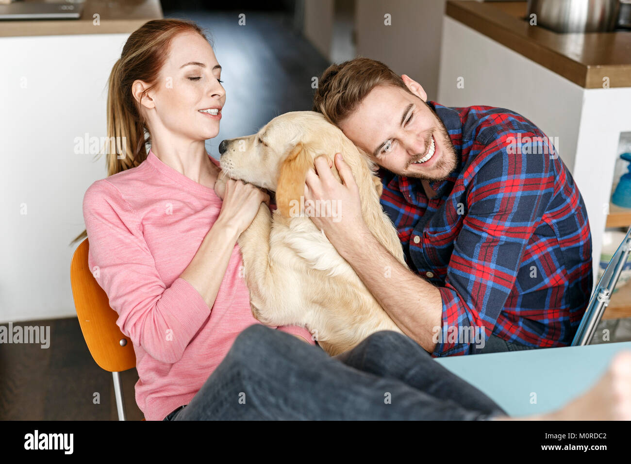 Happy young couple cuddling with dog at home Stock Photo - Alamy