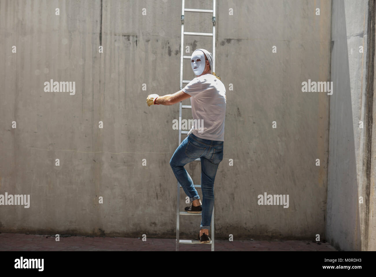 Man wearing a mask climbing a ladder Stock Photo - Alamy