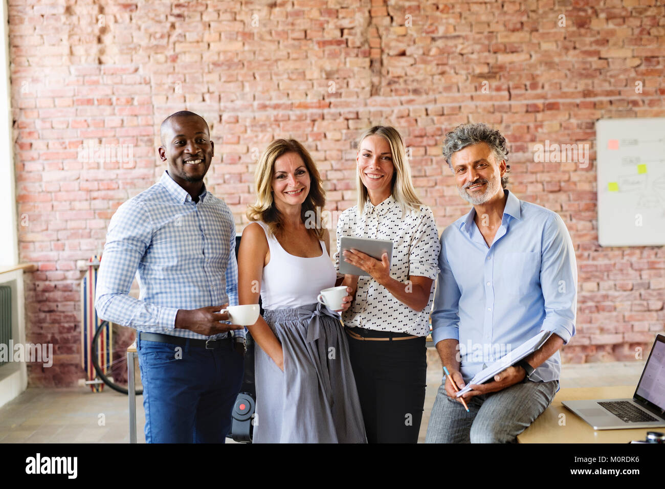 Portrait of smiling colleagues at desk in loft office Stock Photo - Alamy