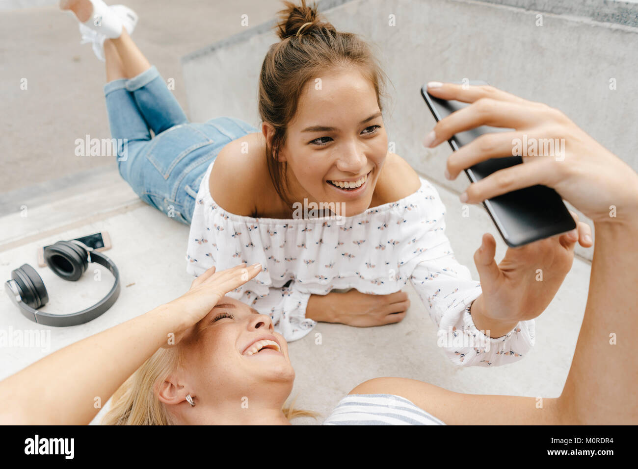 Two happy young women sharing cell phone in a skatepark Stock Photo - Alamy