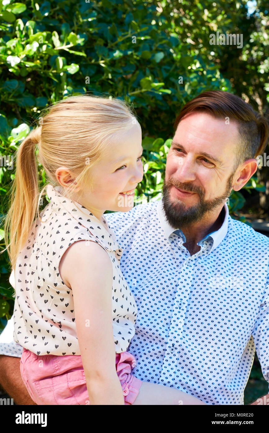 Smiling girl sitting on father's lap Stock Photo - Alamy