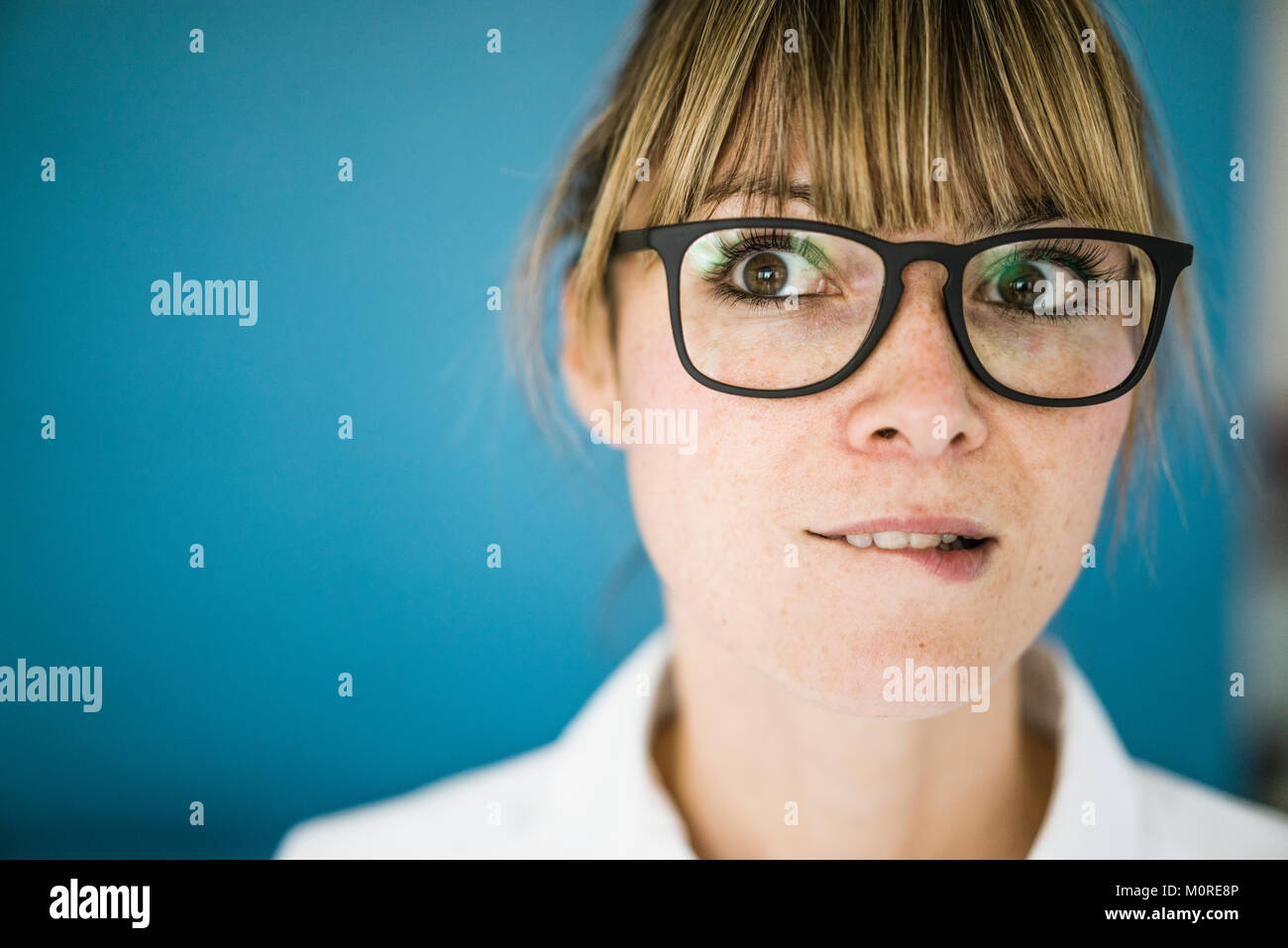 Portrait of woman with glasses biting on her lip Stock Photo - Alamy