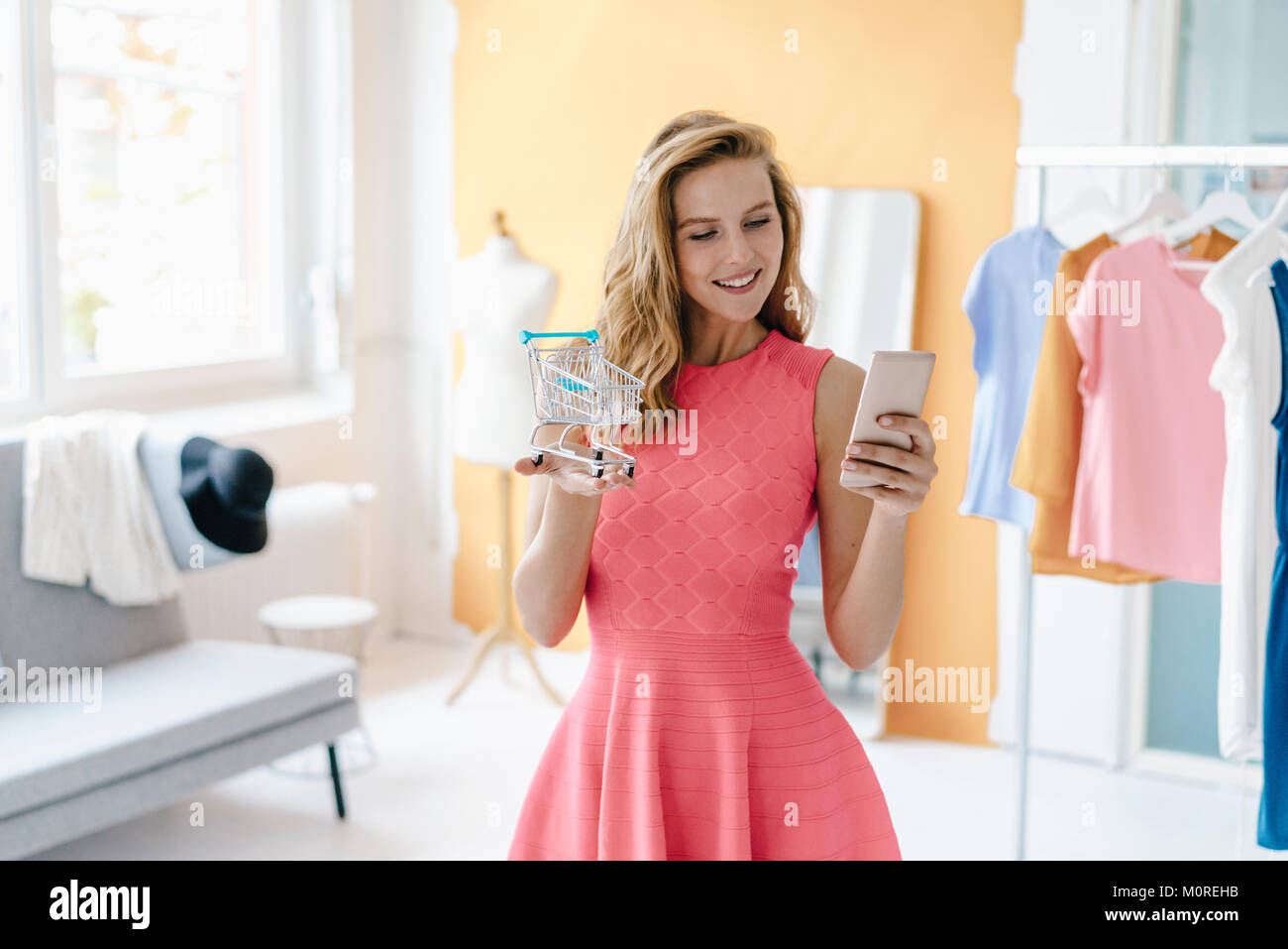 Smiling young woman in fashion studio taking cell phone picture of ...