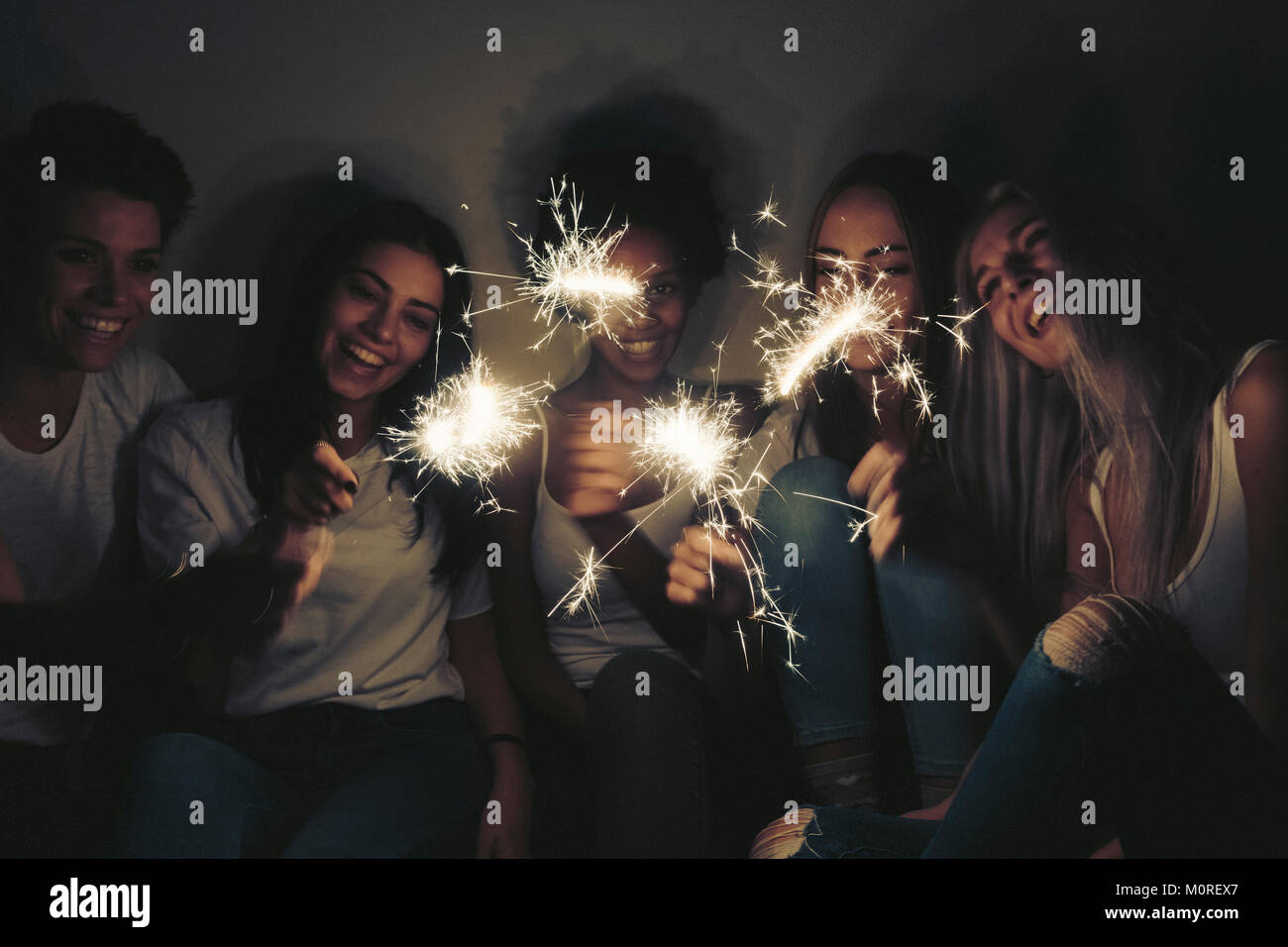 Happy female friends with sparklers in the dark Stock Photo - Alamy