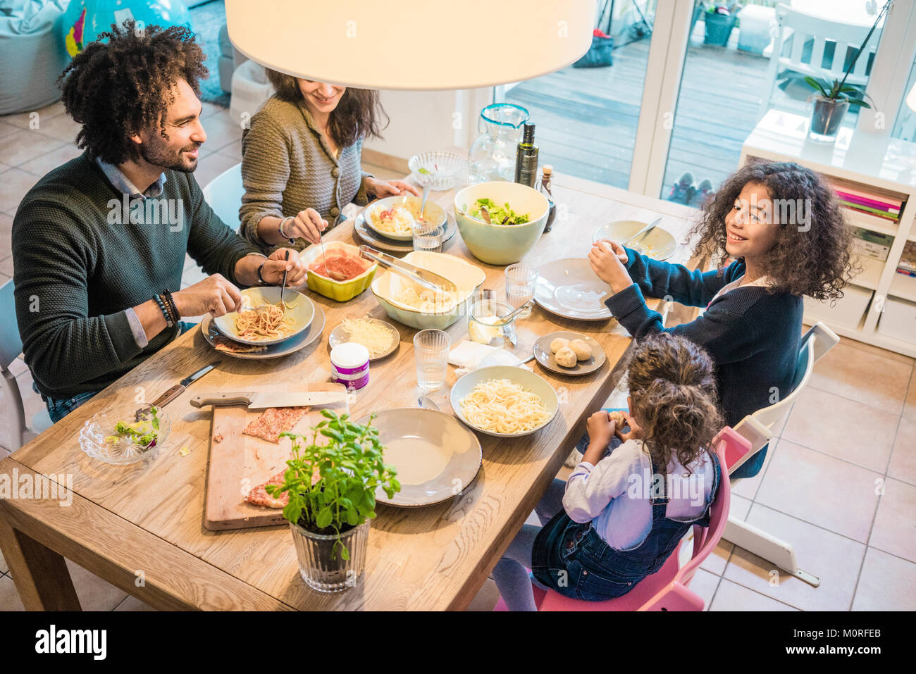 Happy family eating together pizza and pasta Stock Photo - Alamy