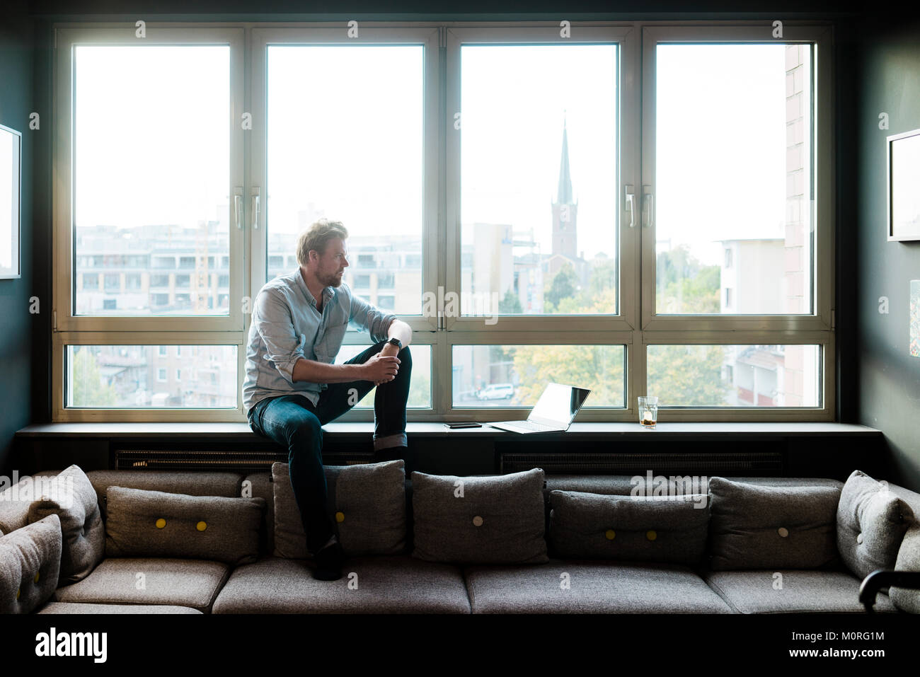Businessman sitting at the window in lounge area of an office Stock ...