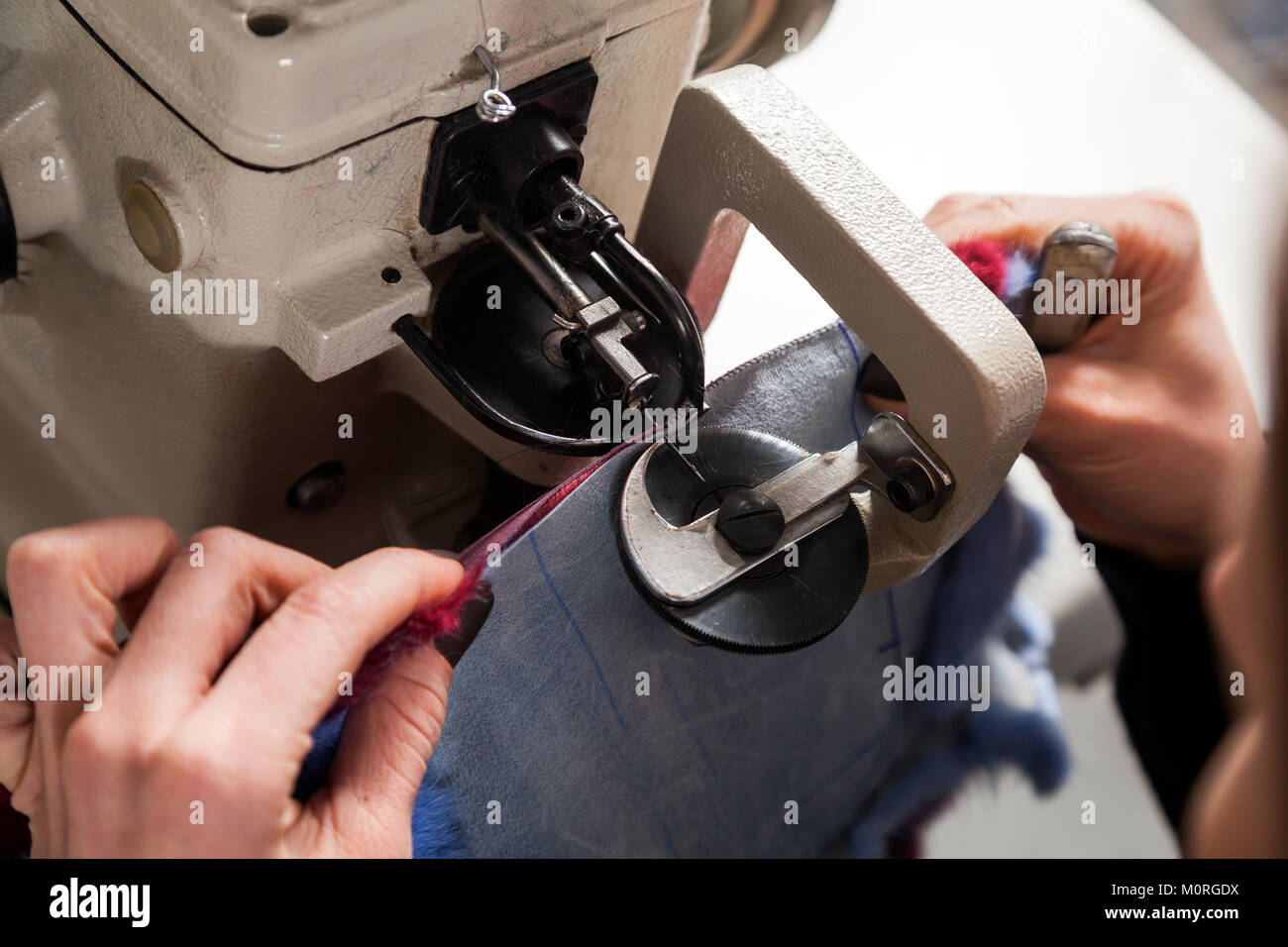 close up of beautiful woman skinner, furrier work at sewing machine for ...