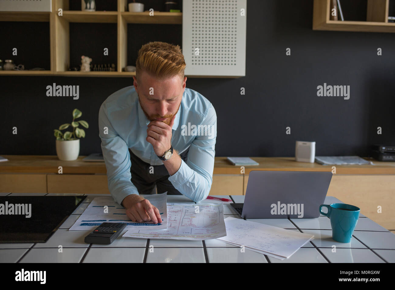 Man with laptop studying plans on table at home Stock Photo - Alamy