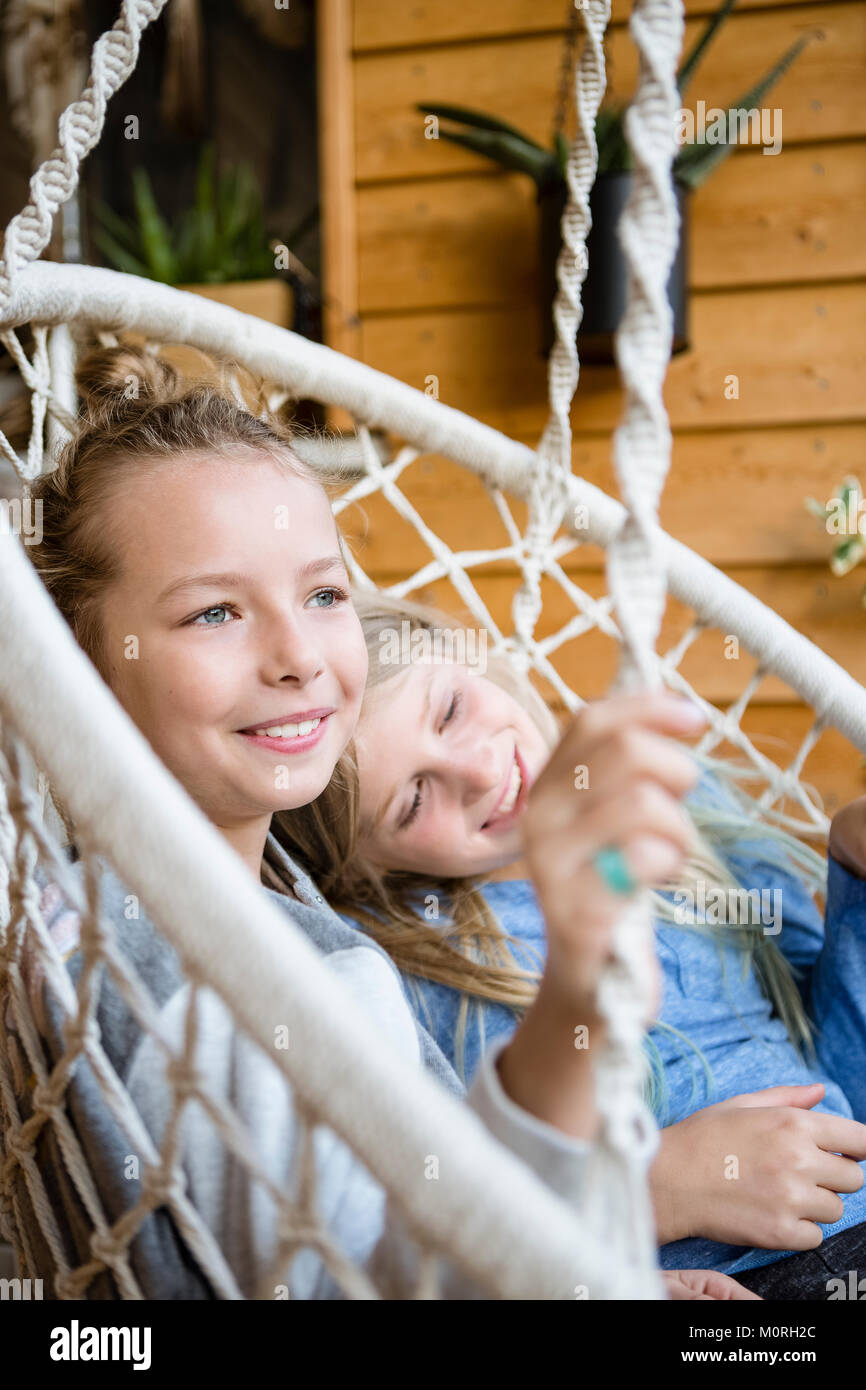 Two happy girls relaxing together in a hanging chair Stock Photo - Alamy