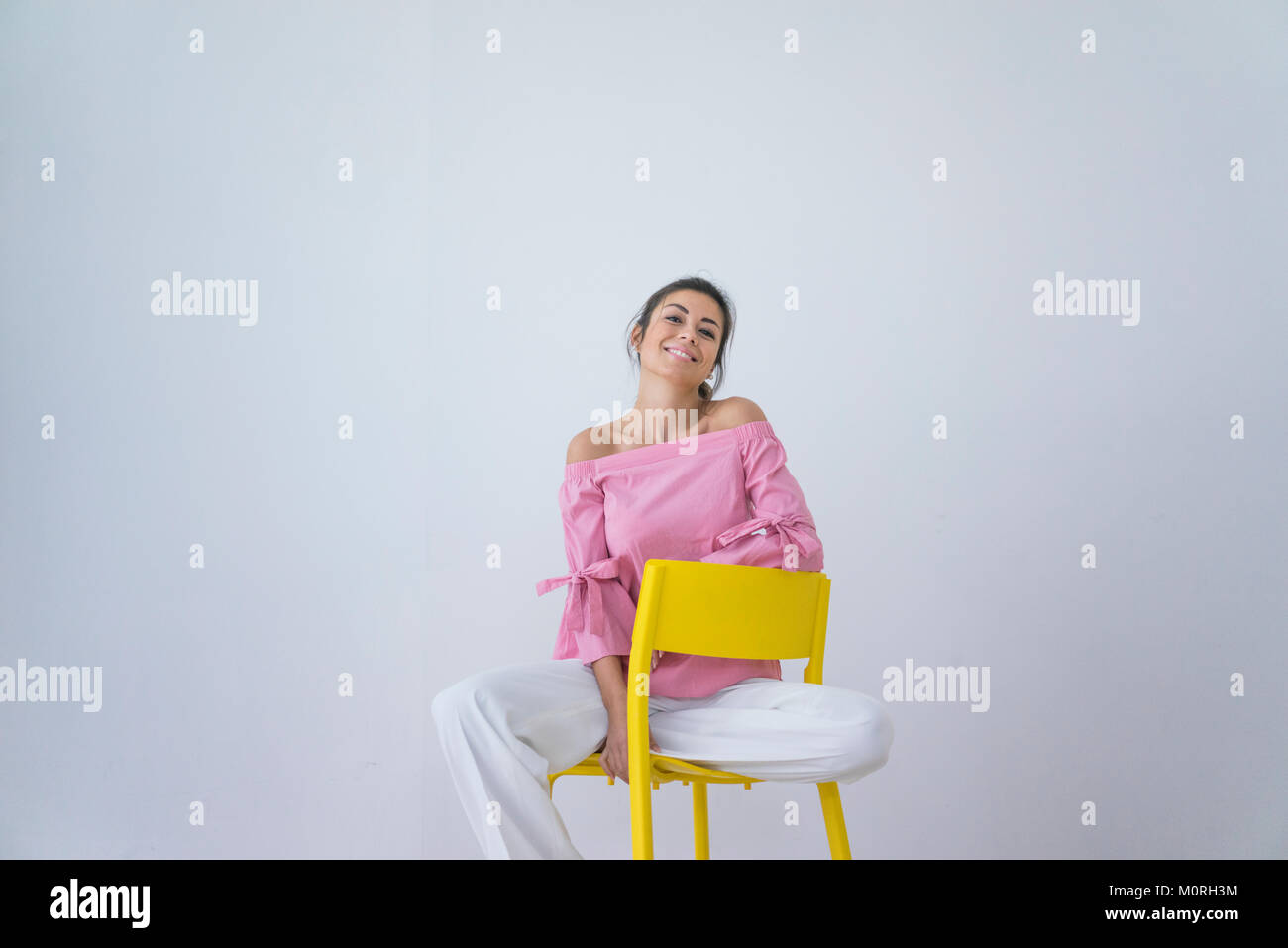Portrait of laughing woman sitting on yellow chair Stock Photo - Alamy