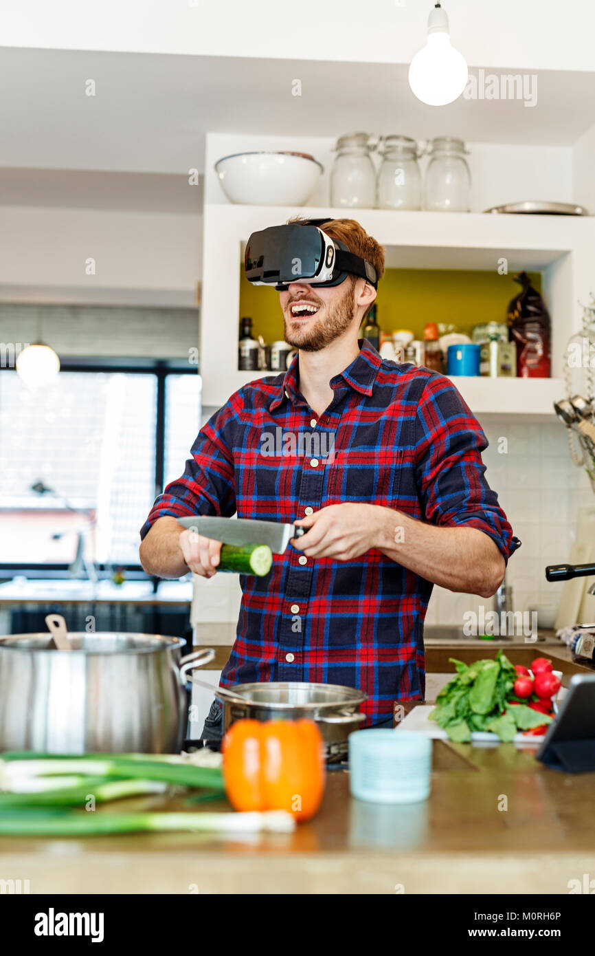 Happy young man wearing VR glasses cooking in kitchen Stock Photo - Alamy