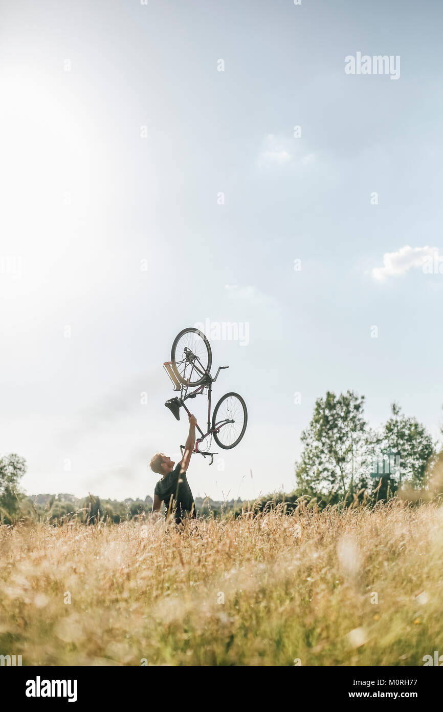 Young man lifting up his bike Stock Photo - Alamy