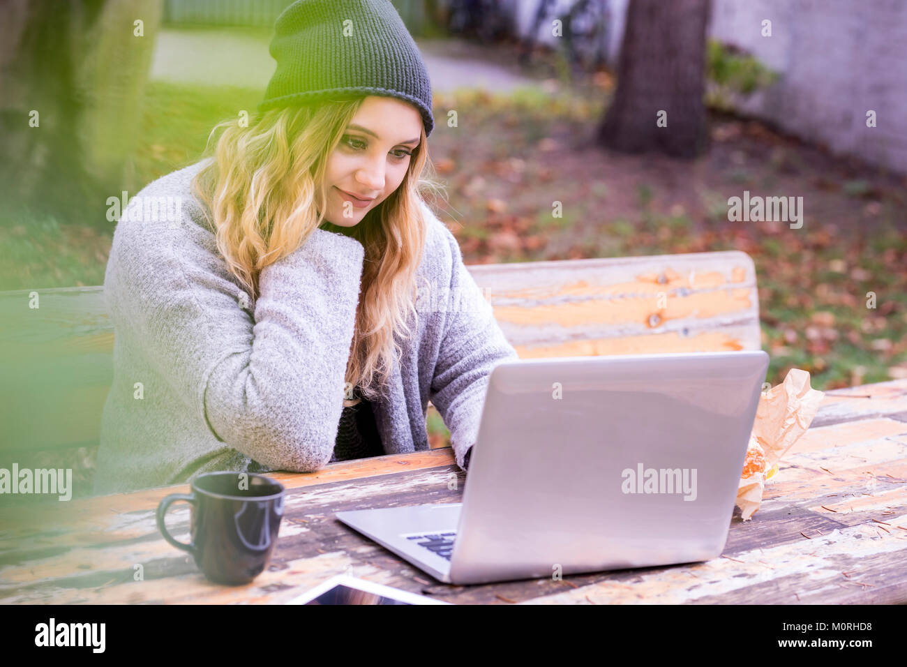 Portrait of smiling young woman with laptop skyping outdoors in autumn ...