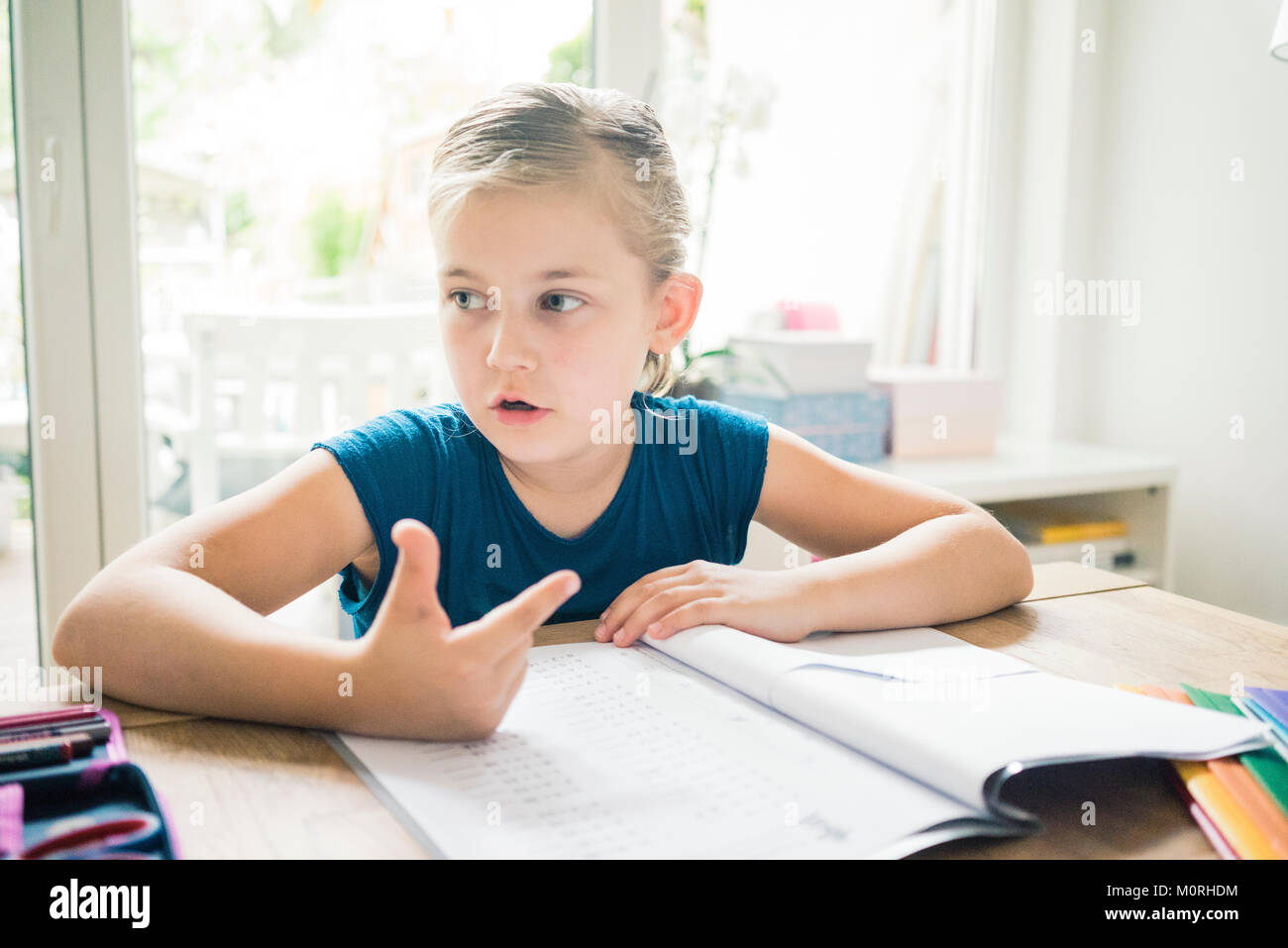 Girl doing homework at table Stock Photo - Alamy