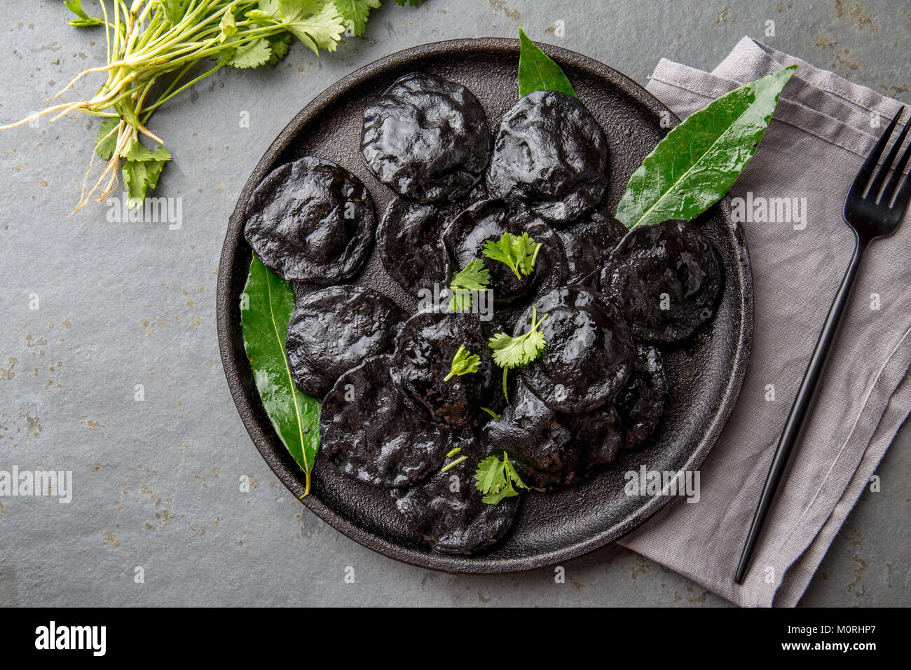 Traditional Italian black ravioli on black plate, gray stone slate ...
