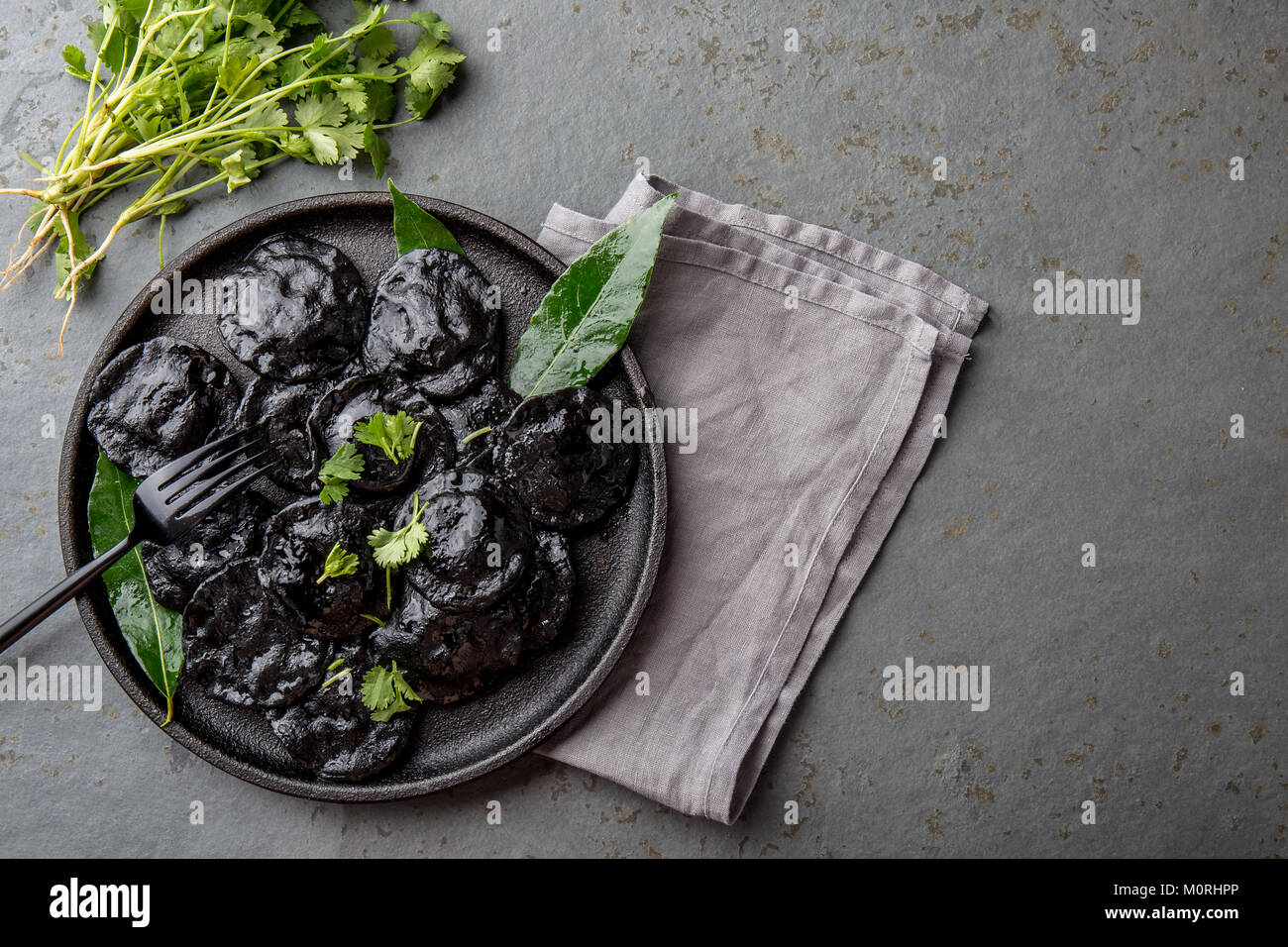 Traditional Italian black ravioli on black plate, gray stone slate ...
