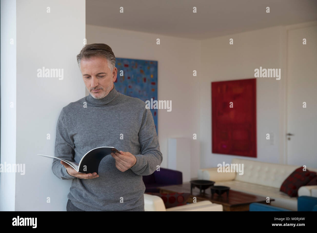 Businessman reading magazine in apartment Stock Photo - Alamy