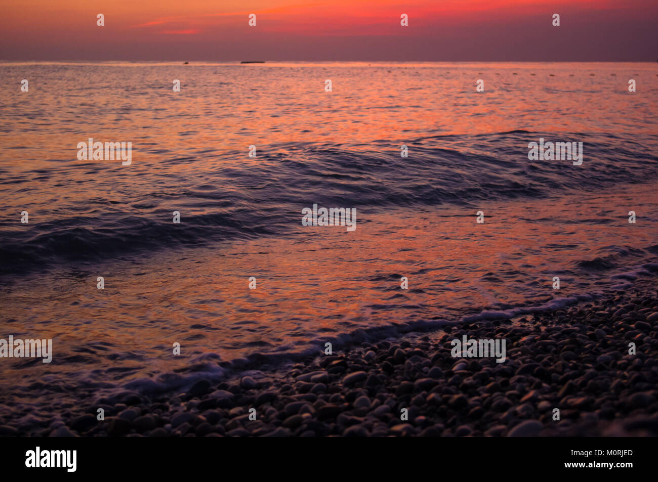 Summer sea sunset on the pebble beach, the sun, waves and clouds ...