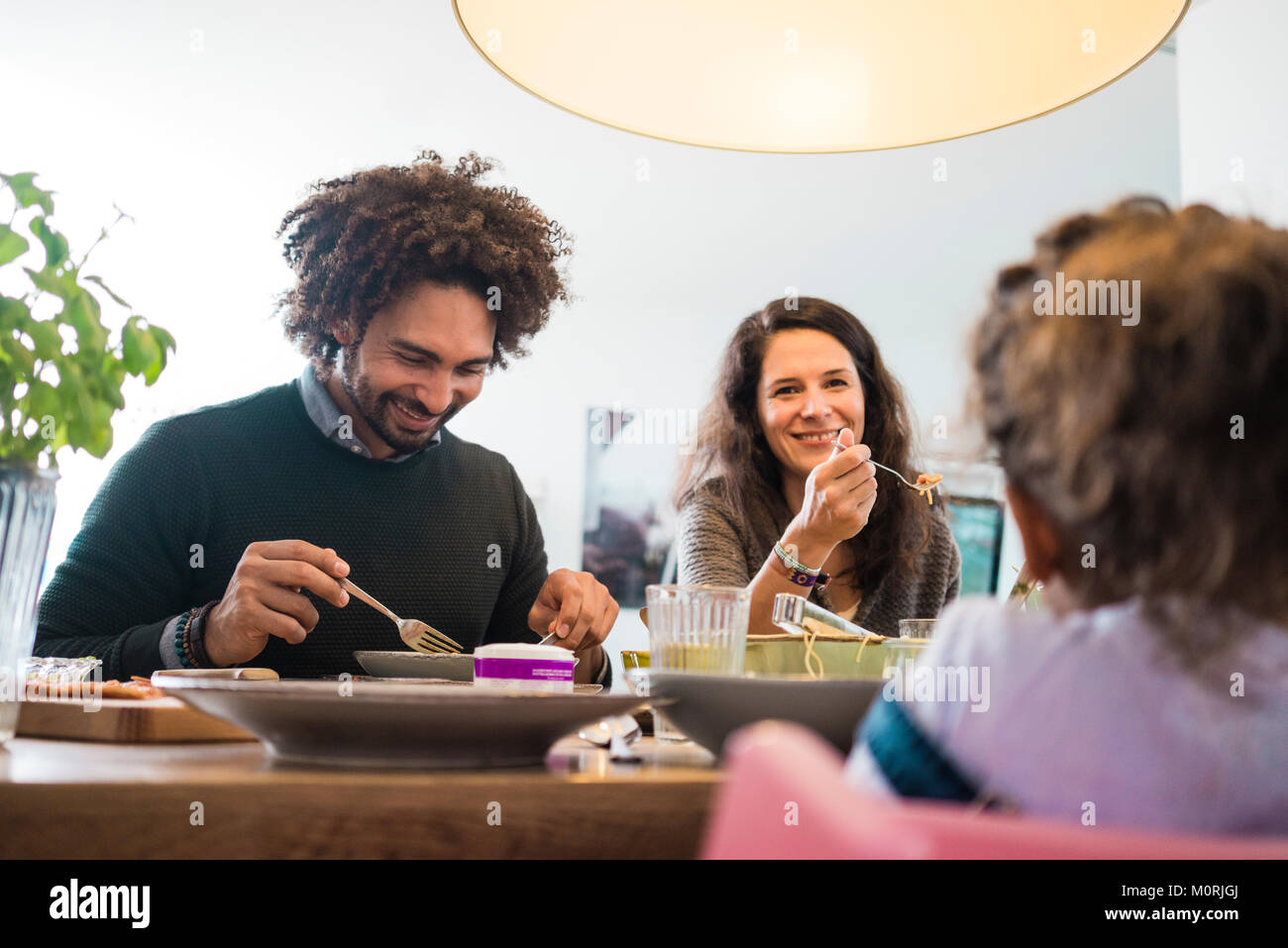 Happy family eating together pizza and pasta Stock Photo - Alamy
