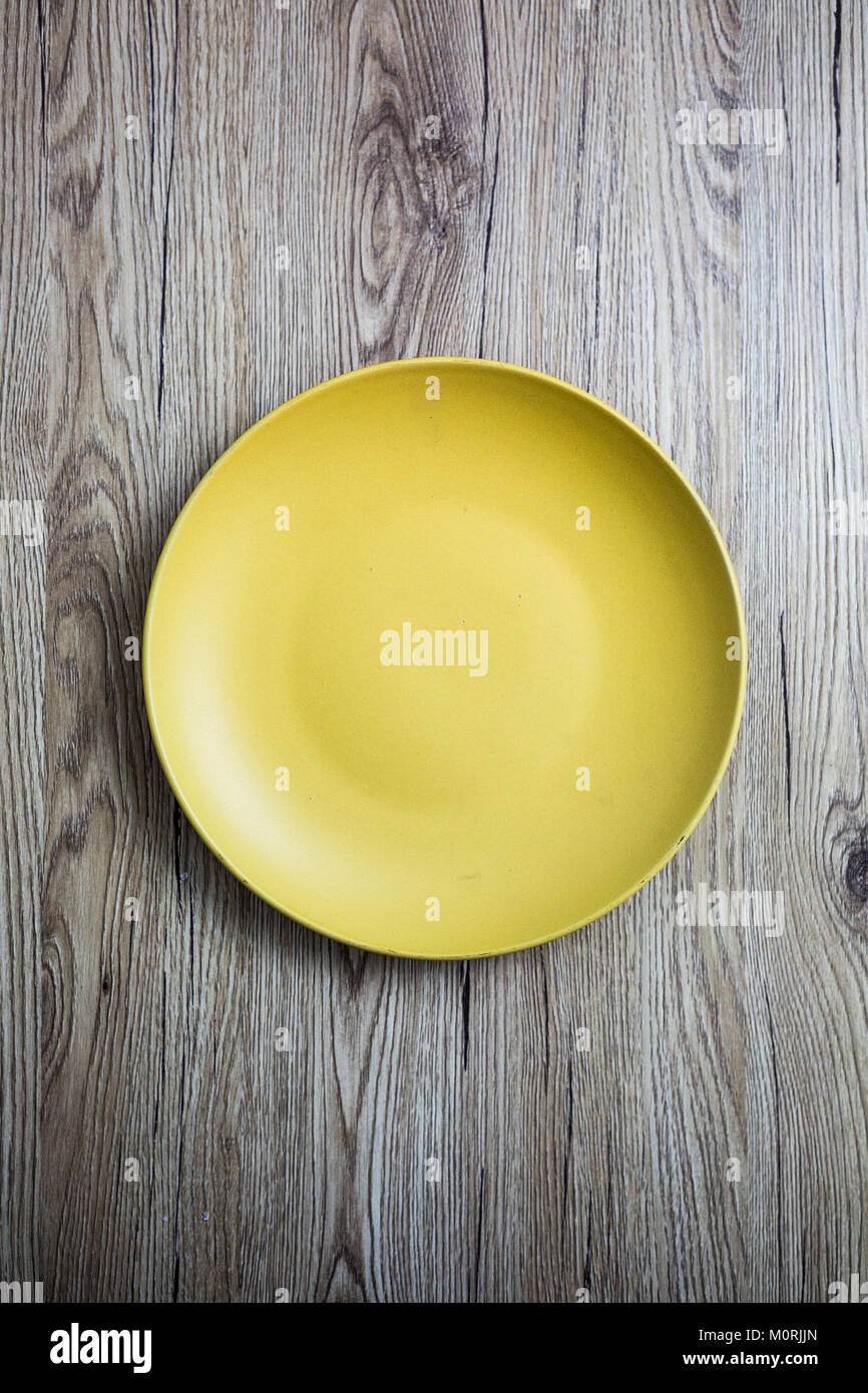 Empty yellow plate on wood Stock Photo - Alamy